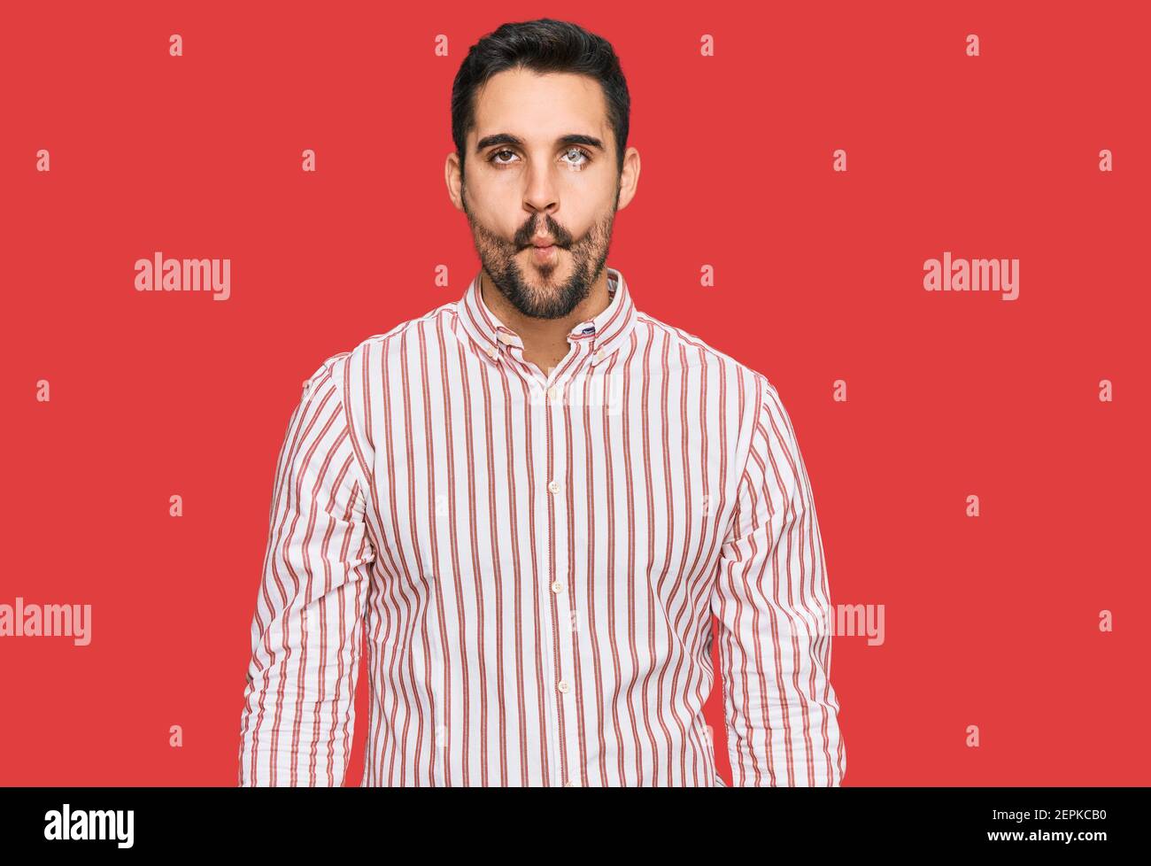 Young hispanic man wearing business shirt making fish face with lips ...