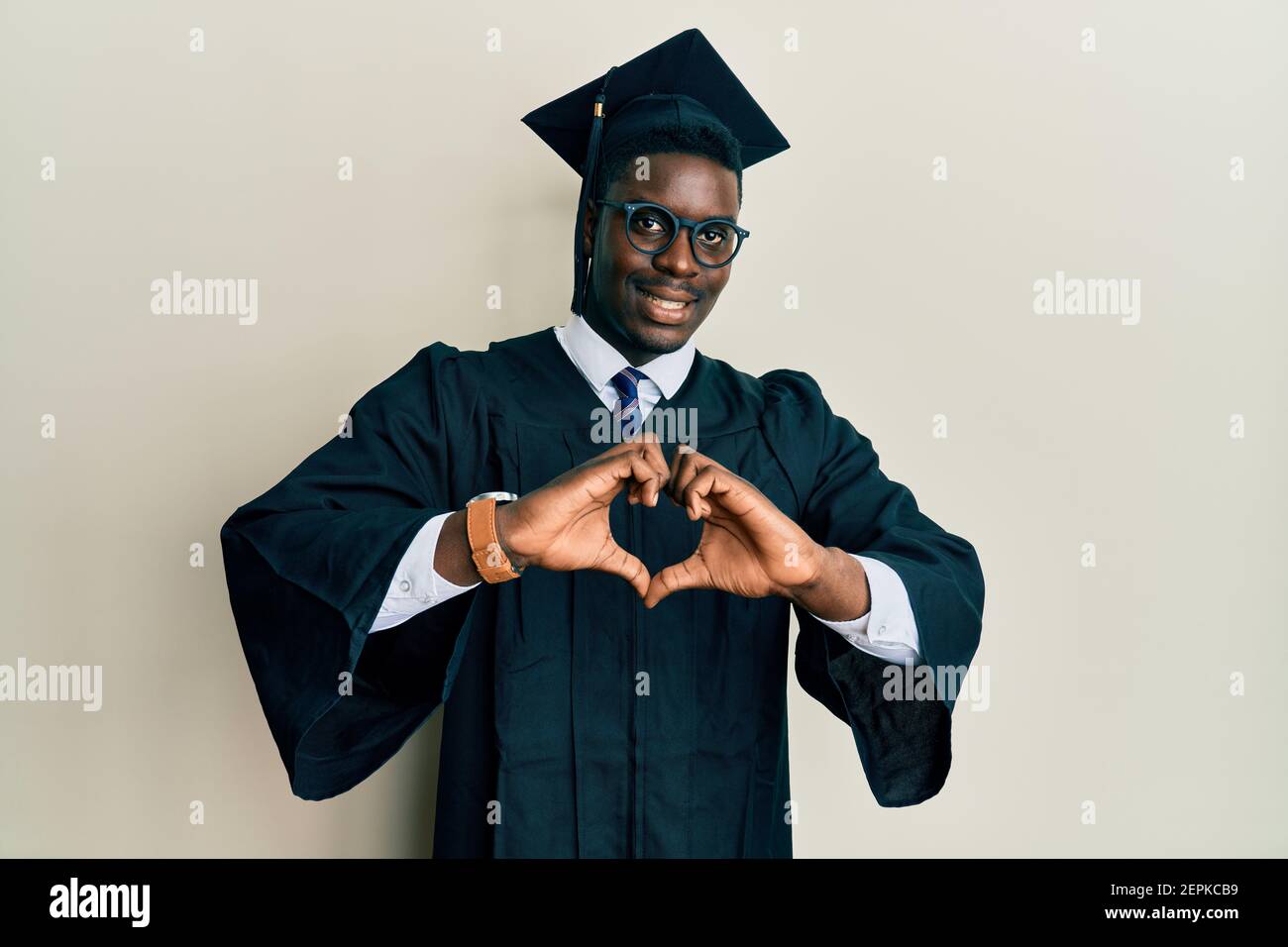 Handsome black man wearing graduation cap and ceremony robe smiling in ...