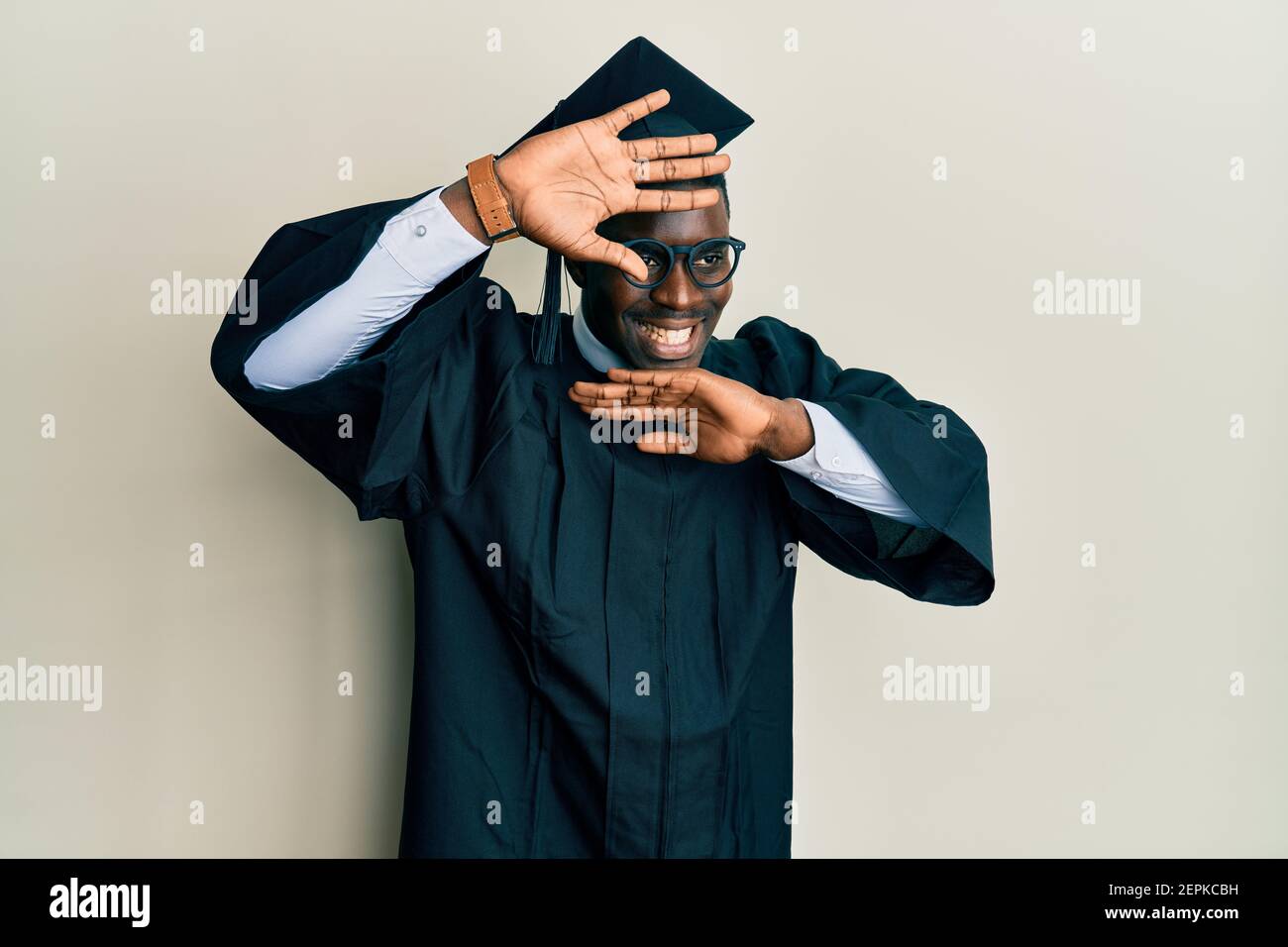 Handsome black man wearing graduation cap and ceremony robe smiling ...