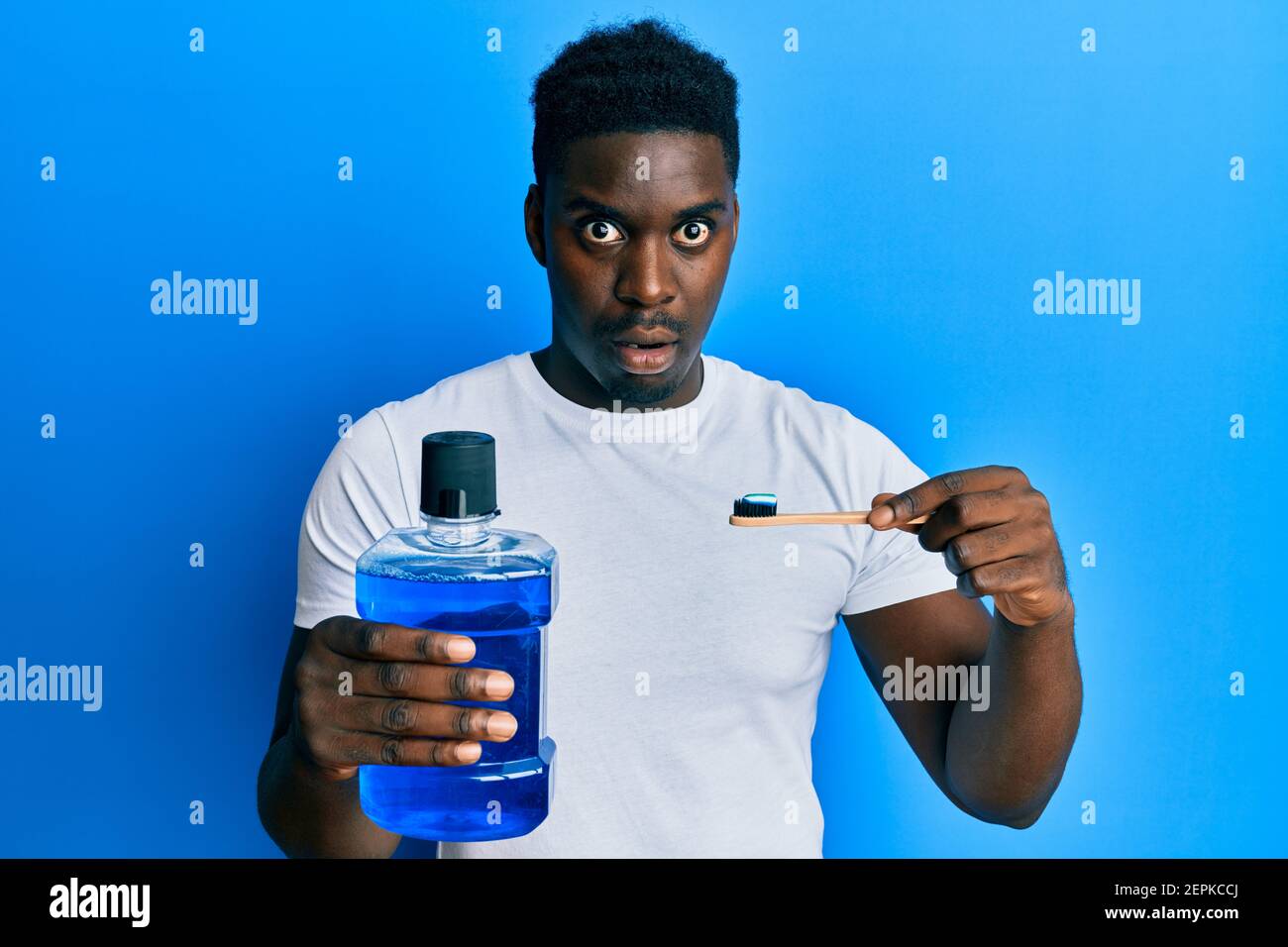 Handsome black man holding mouthwash and toothbrush for fresh breath ...
