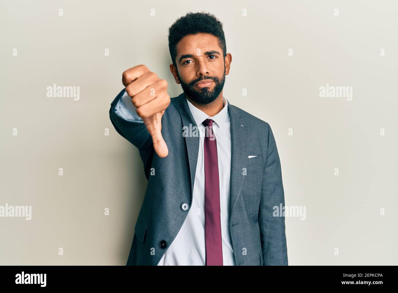 Handsome hispanic man with beard wearing business suit and tie looking ...