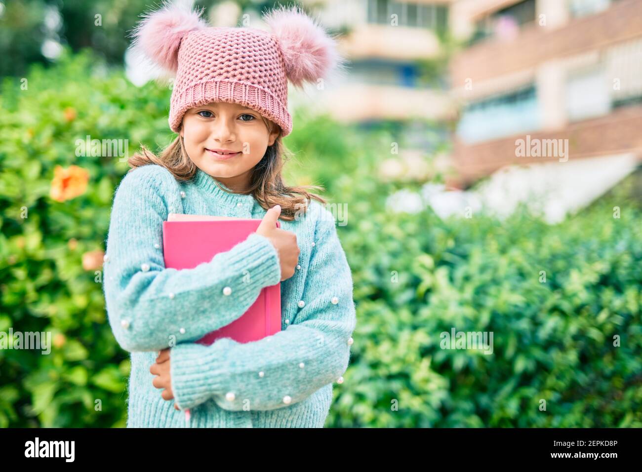 Adorable student child girl smiling happy holding book at the park ...