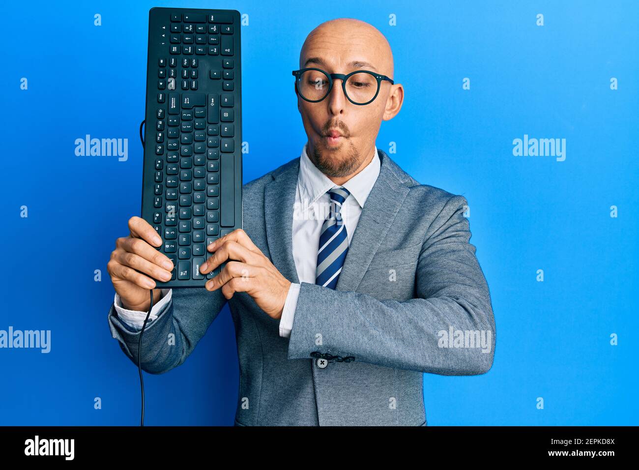 Bald man with beard holding keyboard making fish face with mouth and ...