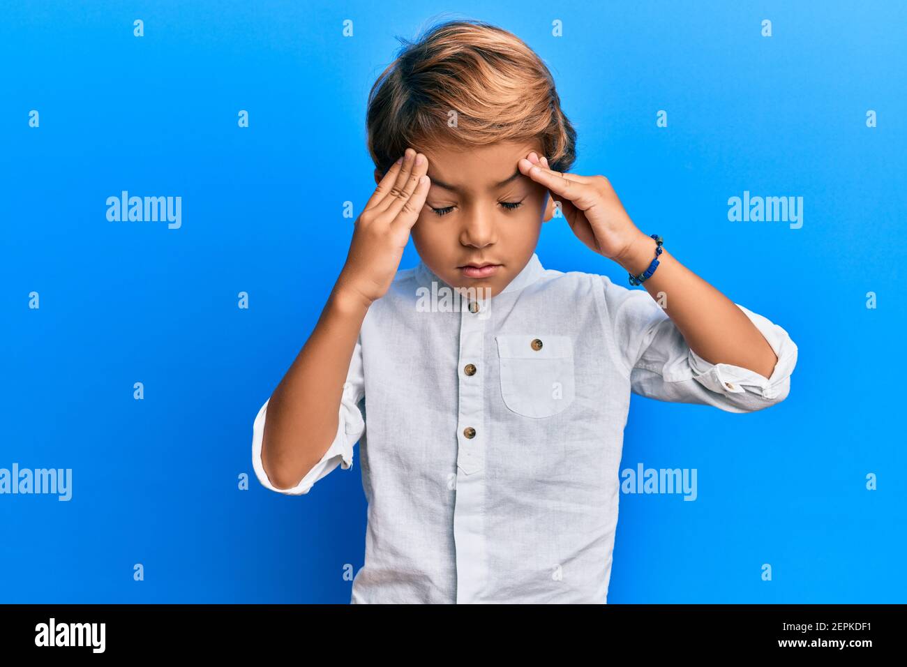 Adorable latin kid wearing casual clothes with hand on head, headache ...