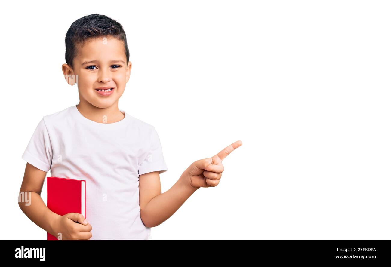 Little cute boy kid reading a book smiling happy pointing with hand and ...