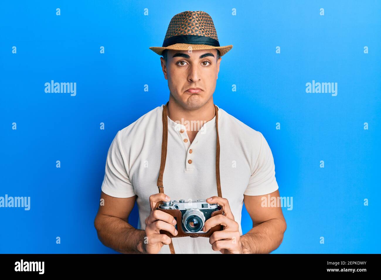 Hispanic young man holding vintage camera depressed and worry for ...