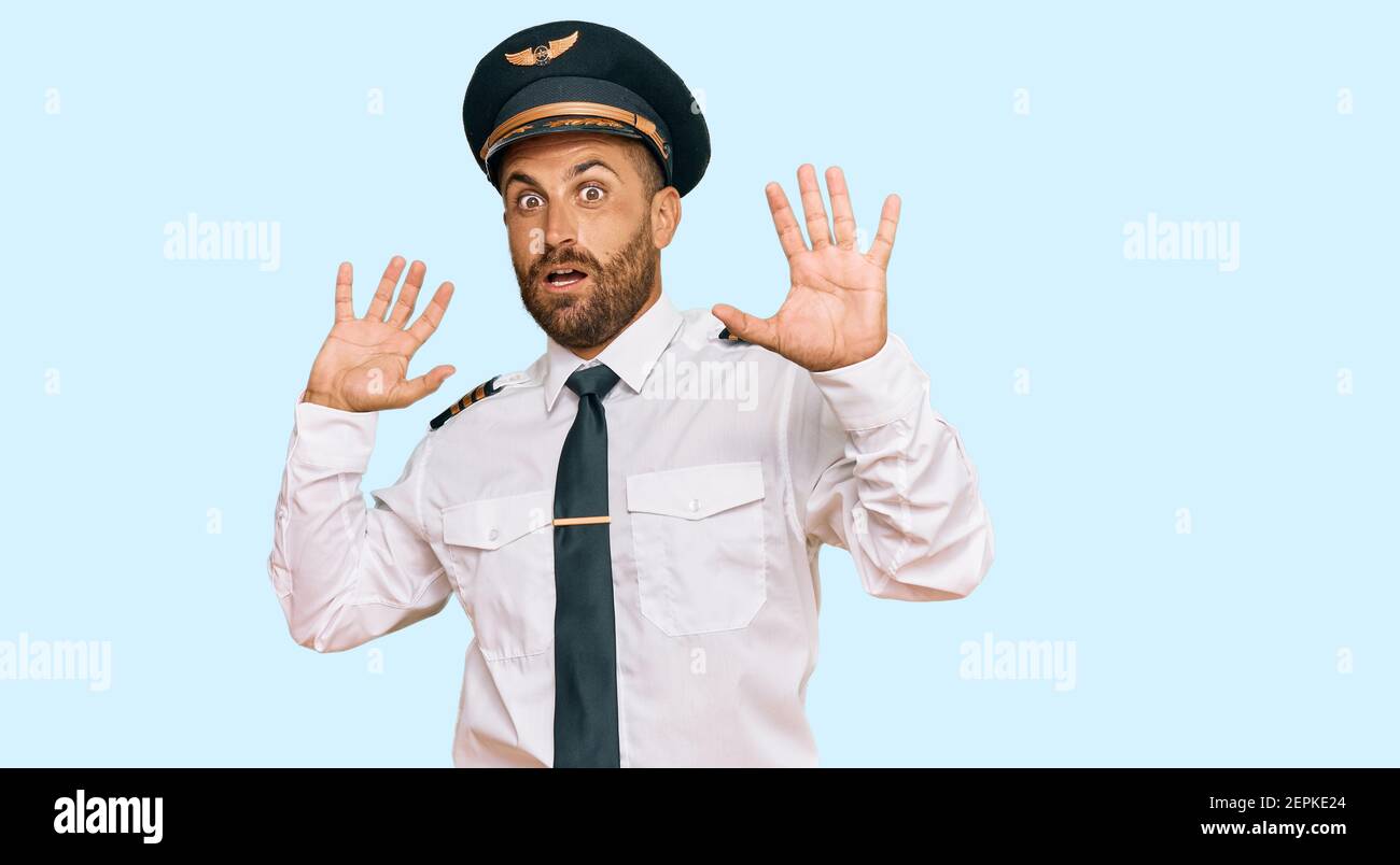 Handsome man with beard wearing airplane pilot uniform afraid and ...