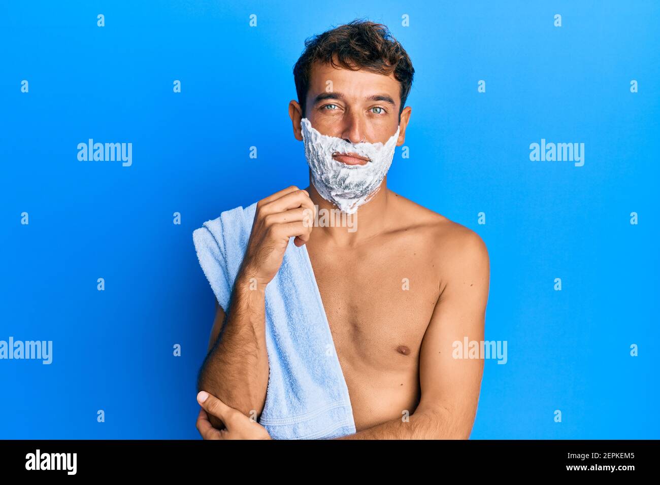 Handsome man saving beard with shave foam over face thinking looking ...
