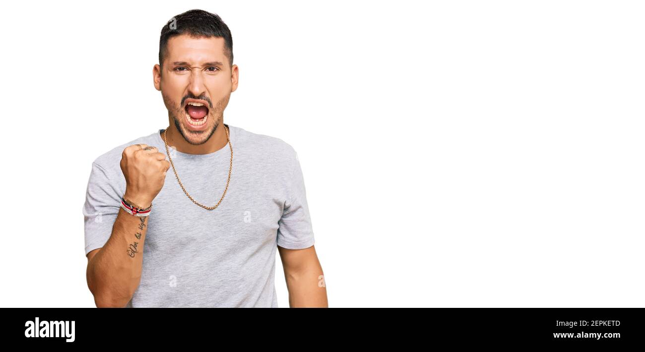 Handsome man with tattoos wearing 90s style angry and mad raising fist ...