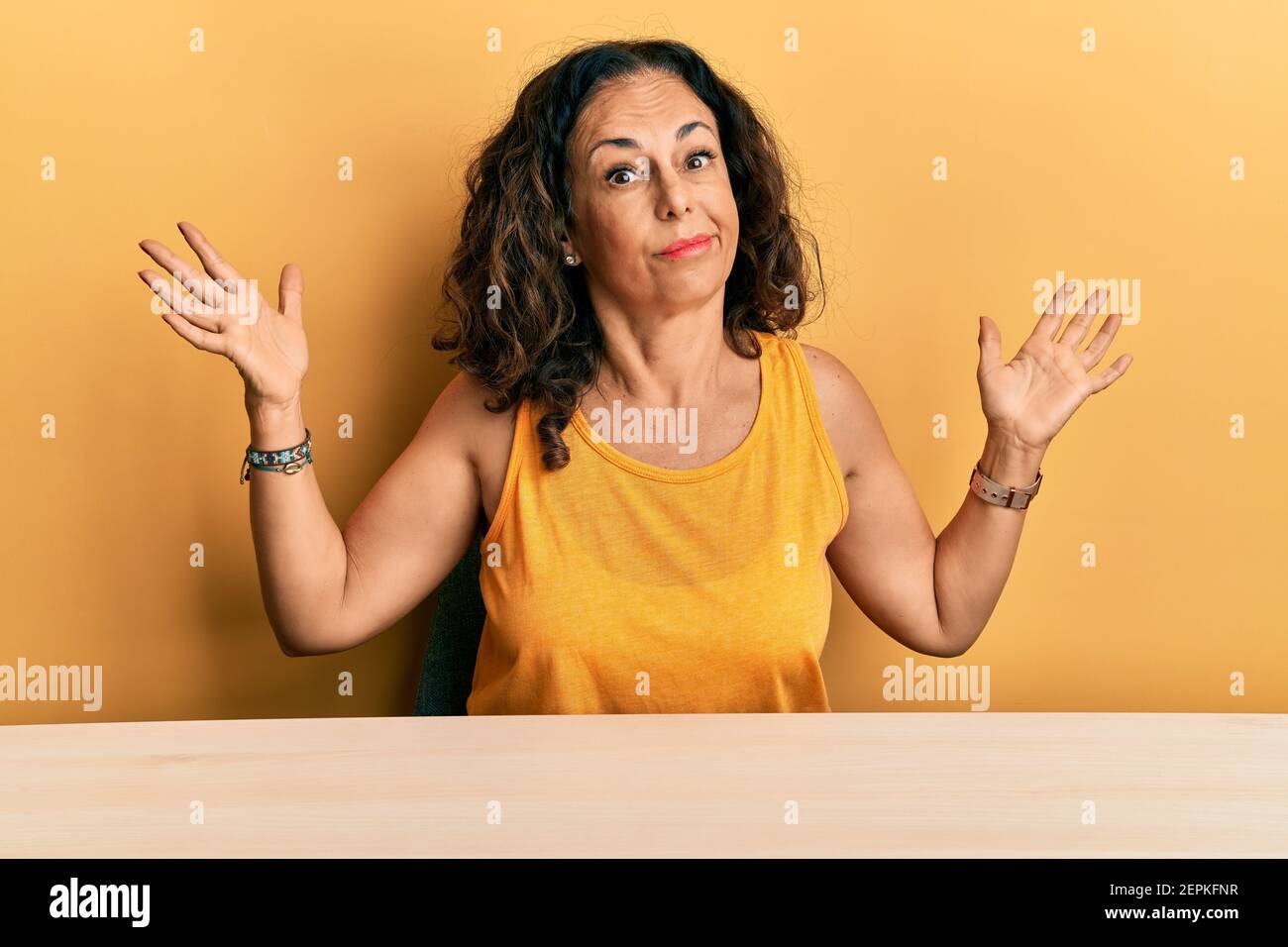 Beautiful middle age woman wearing casual clothes sitting on the table ...