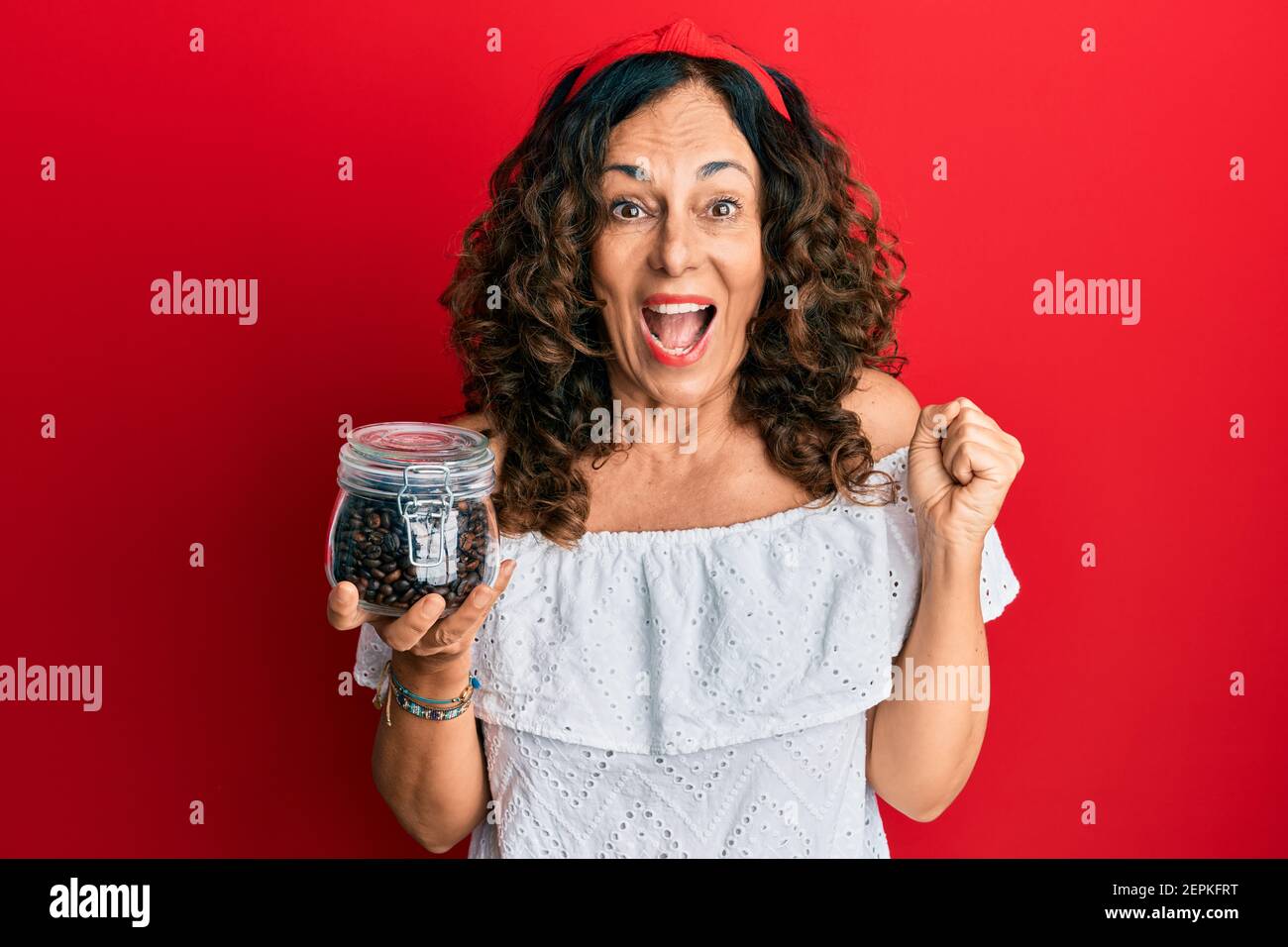 Middle age hispanic woman holding jar with coffee beans screaming proud ...