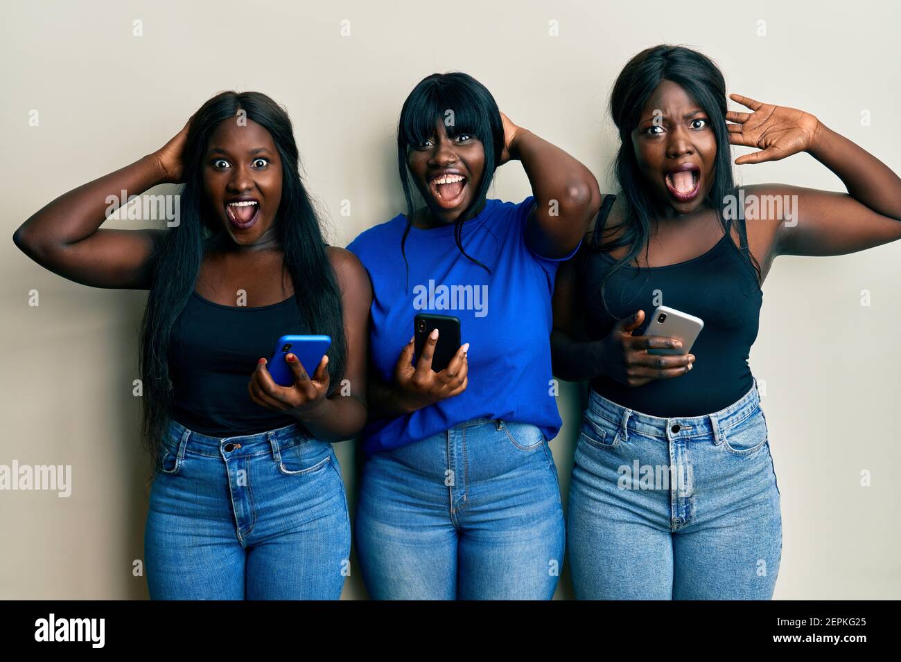 Three young african american friends using smartphone crazy and scared ...