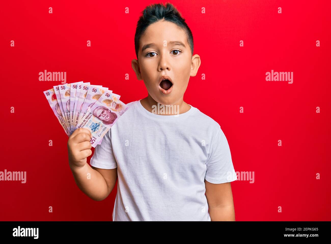 Little boy hispanic kid holding 50 mexican pesos banknotes scared and ...