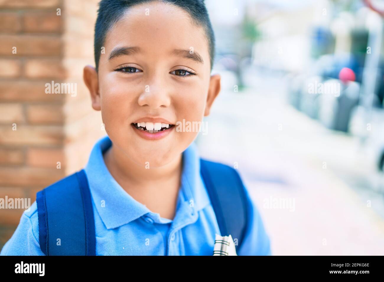 Adorable student boy smiling happy holding book at street of city Stock ...