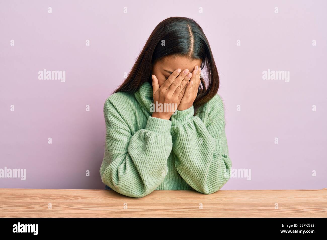 Beautiful hispanic woman wearing casual clothes sitting on the table ...