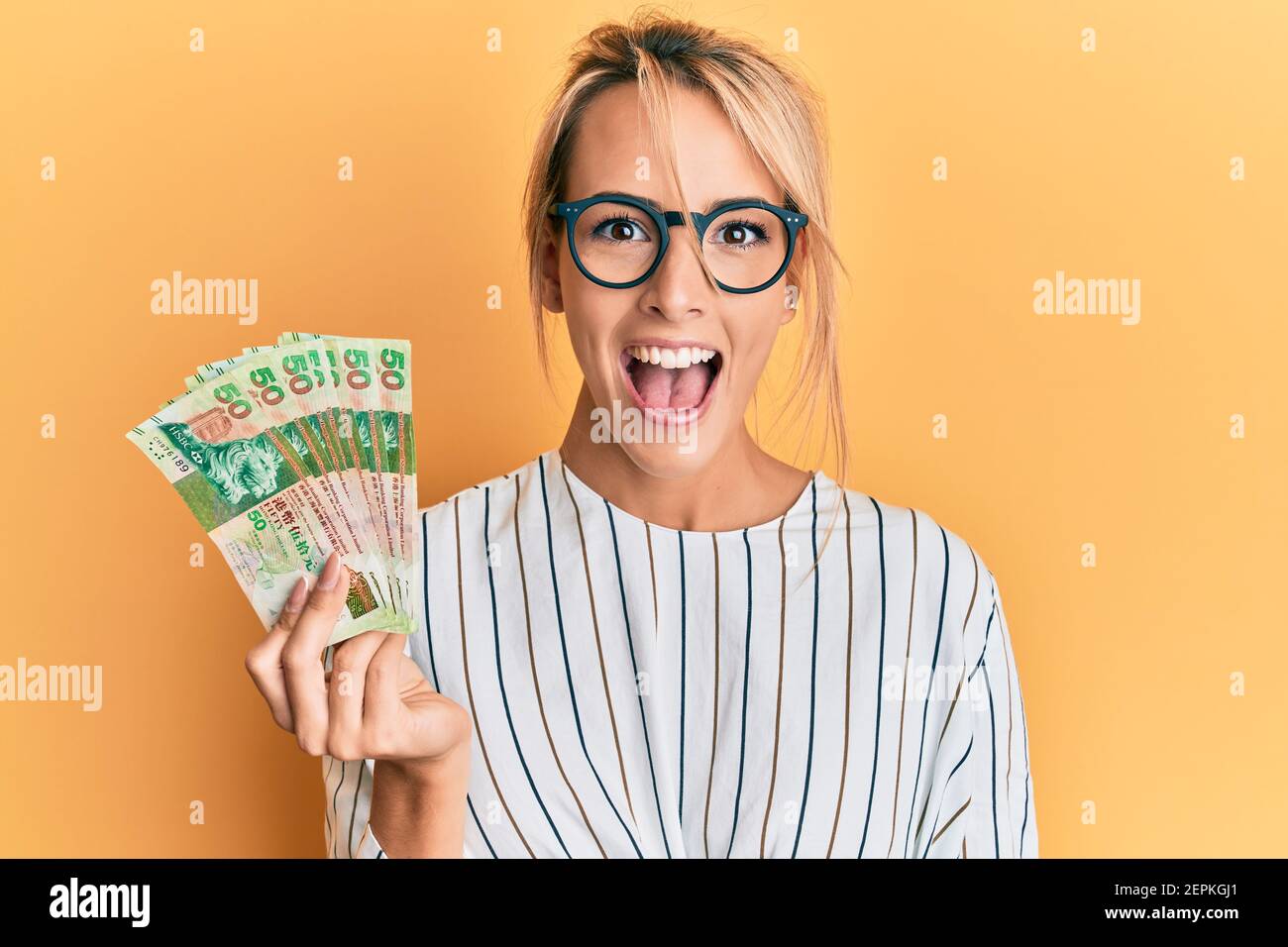 Beautiful blonde woman holding hong kong 50 dollars banknotes looking ...