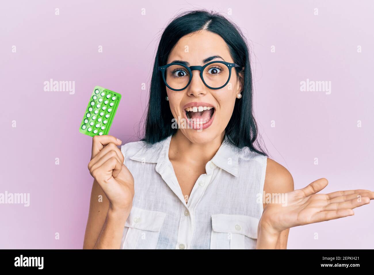Beautiful young woman holding birth control pills celebrating ...