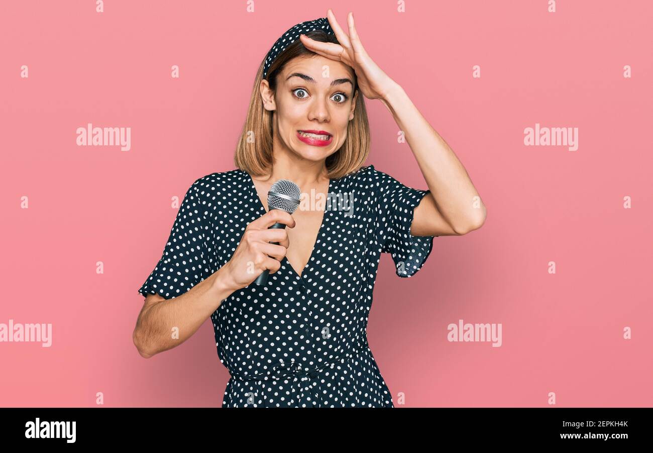 Young blonde girl singing song using microphone stressed and frustrated ...