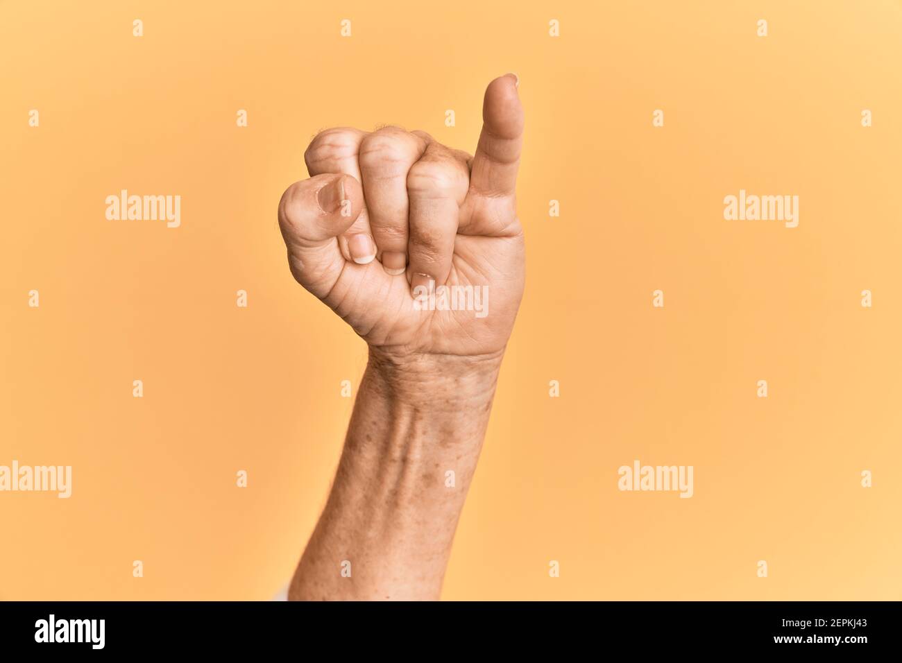 Senior caucasian hand over yellow isolated background showing little ...