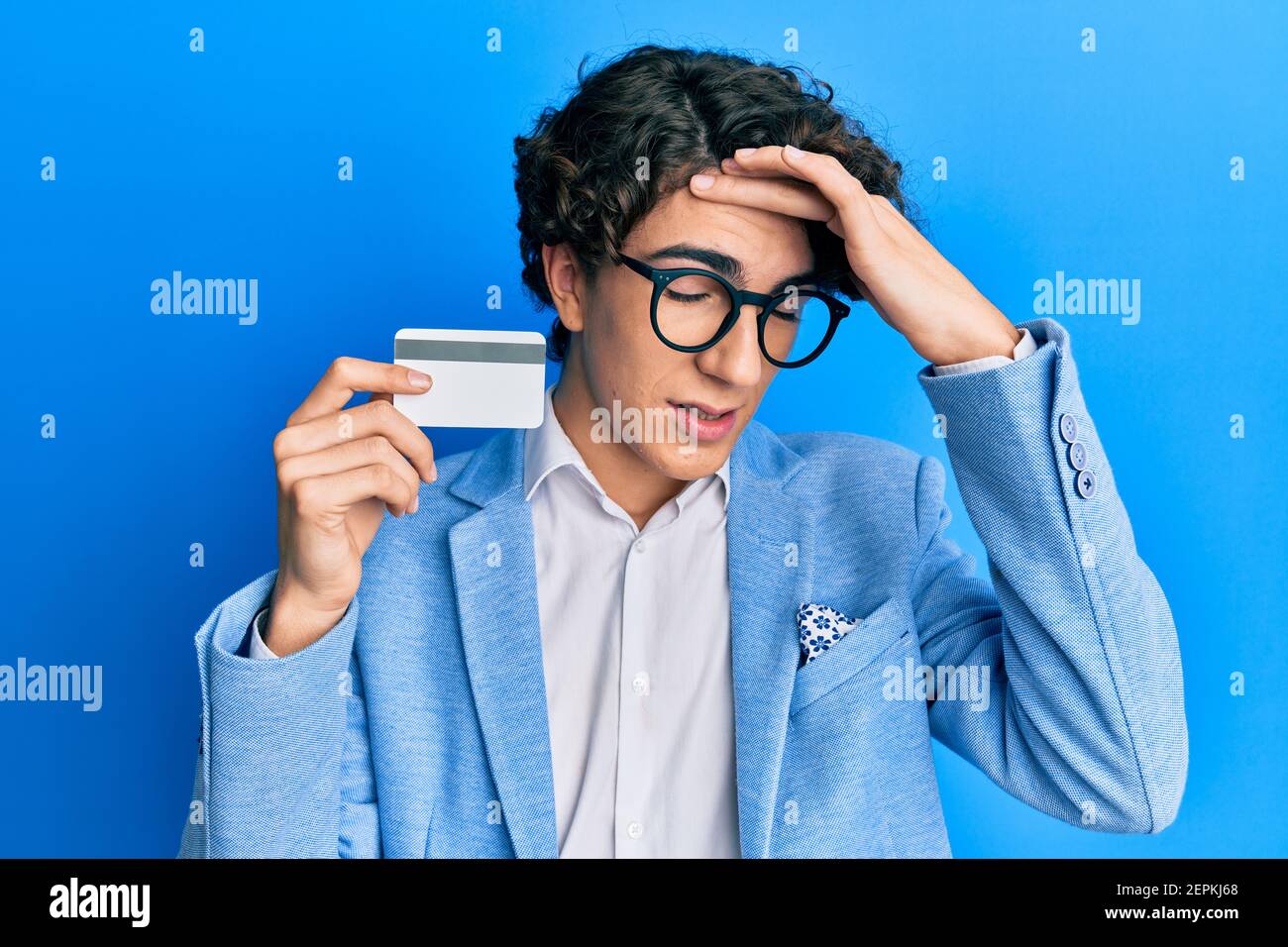 Hispanic young man holding credit card stressed and frustrated with ...