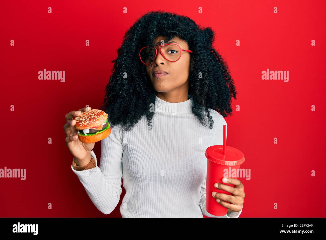 African american woman with afro hair eating a tasty classic burger and ...