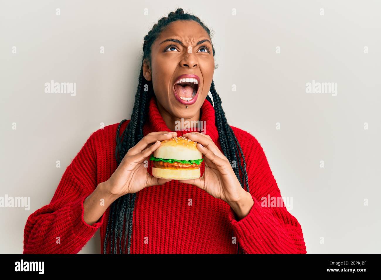 African american woman with braids eating hamburger angry and mad ...