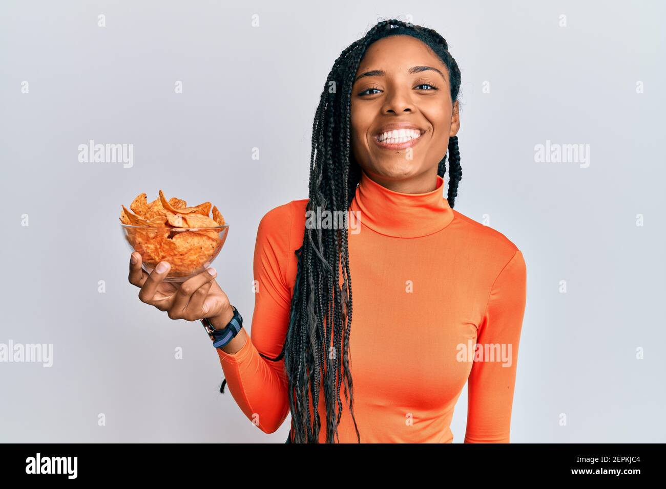 African american woman holding nachos potato chips looking positive and ...