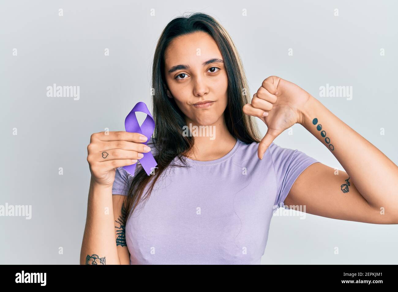 Young hispanic woman holding purple ribbon awareness with angry face ...