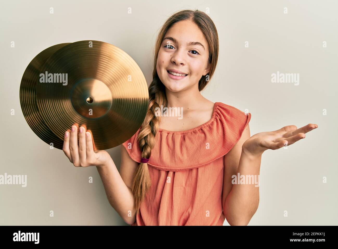 Beautiful brunette little girl holding golden cymbal plates celebrating ...