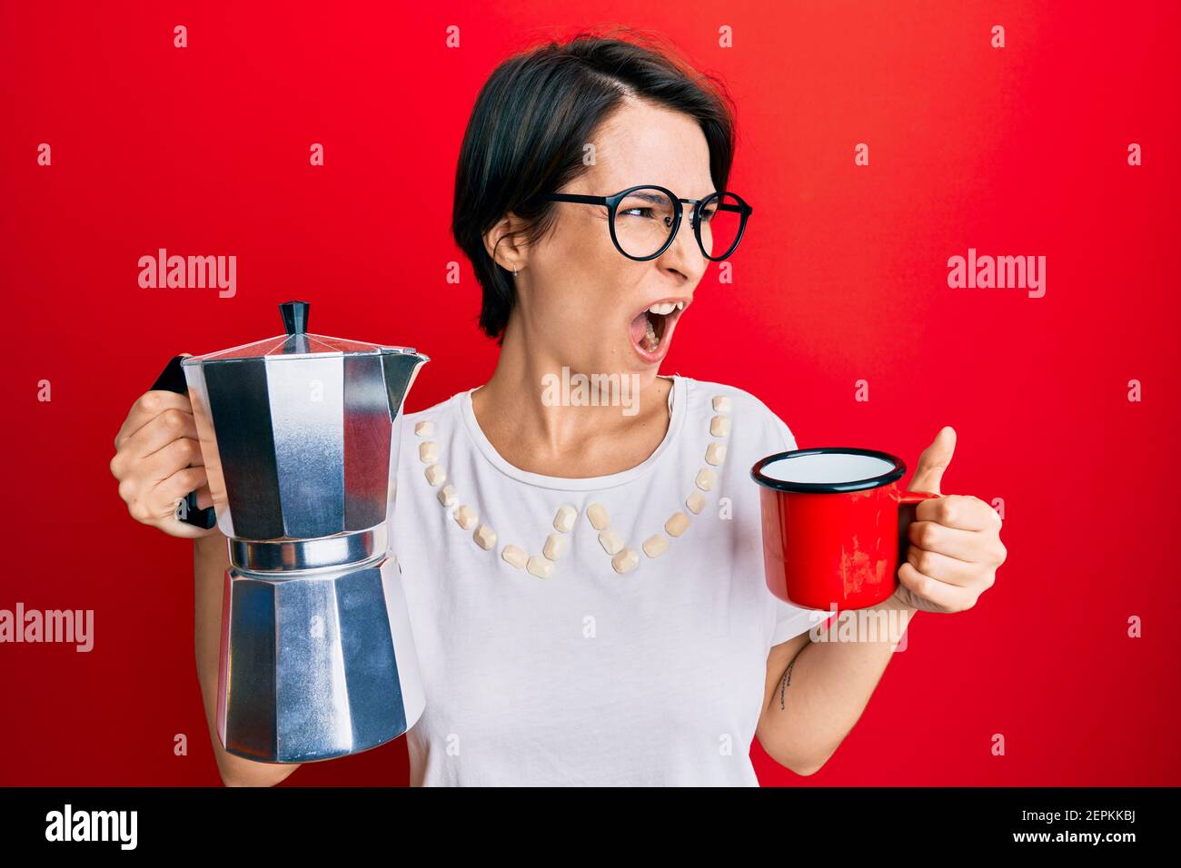 Young brunette woman with short hair drinking italian coffee angry and ...