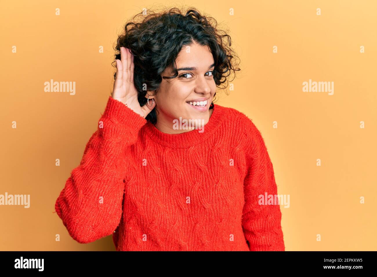Young hispanic woman with curly hair wearing casual winter sweater ...