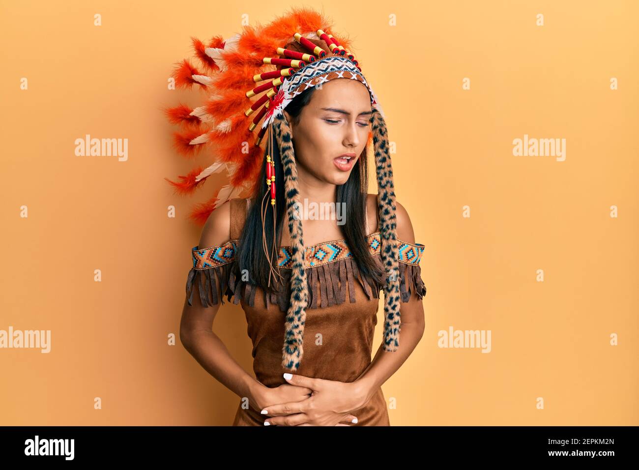 Young brunette woman wearing indian costume with hand on stomach ...