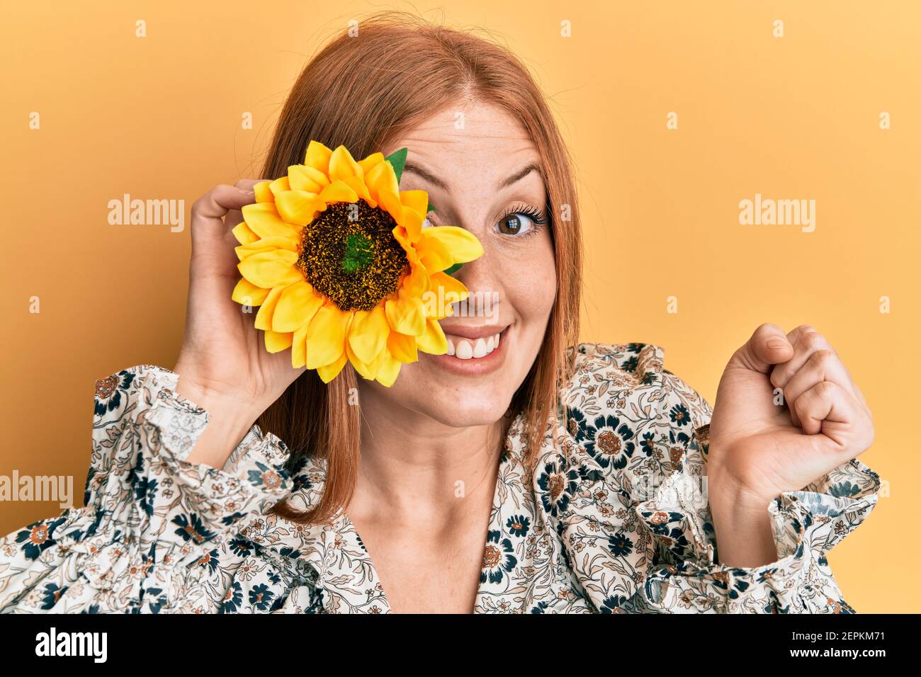 Young irish woman holding sunflower over eye screaming proud ...