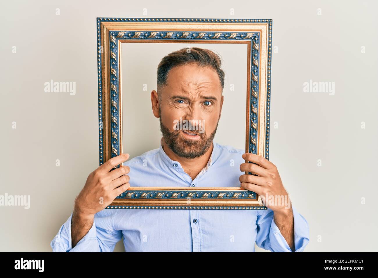 Handsome middle age man holding blank empty banner clueless and ...