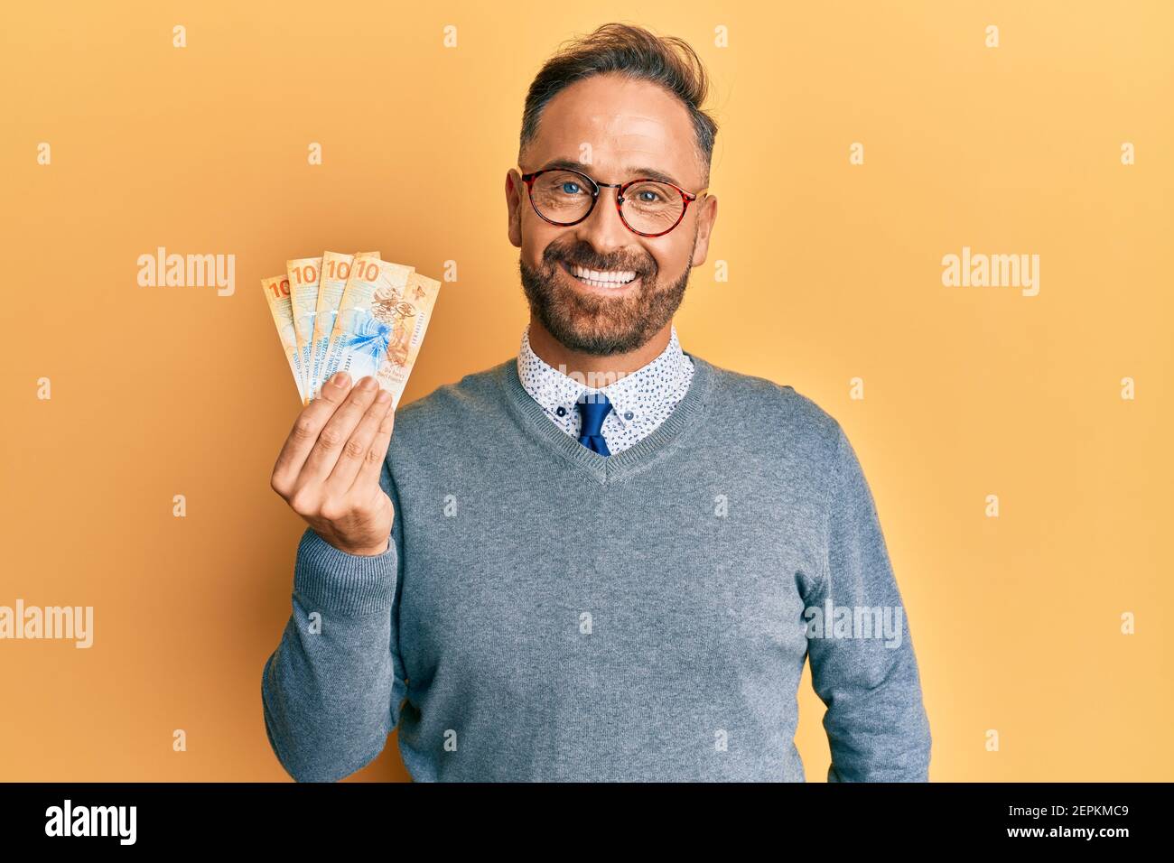 Handsome middle age man holding swiss franc banknotes looking positive ...