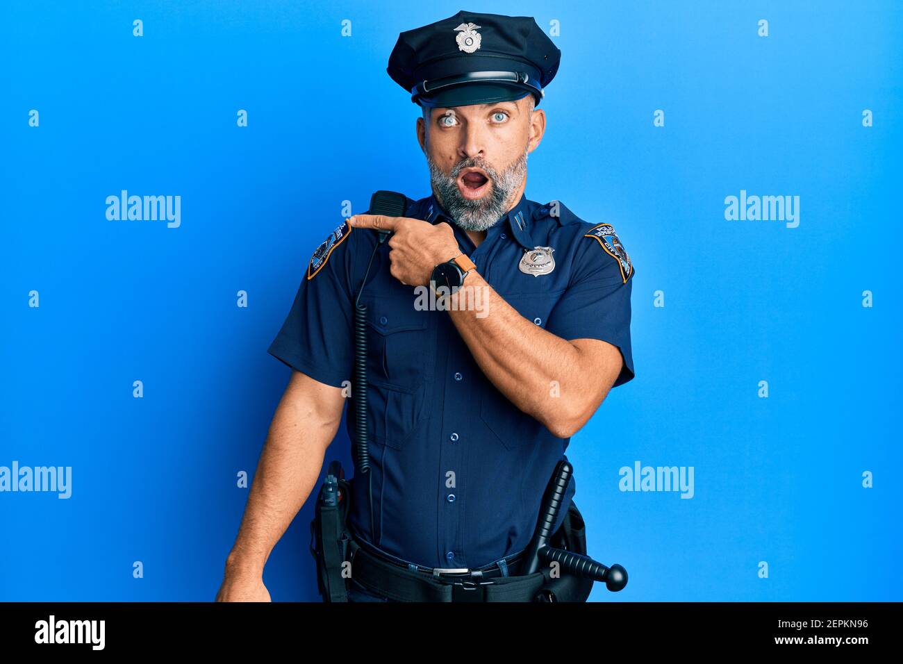 Middle age handsome man wearing police uniform surprised pointing with ...