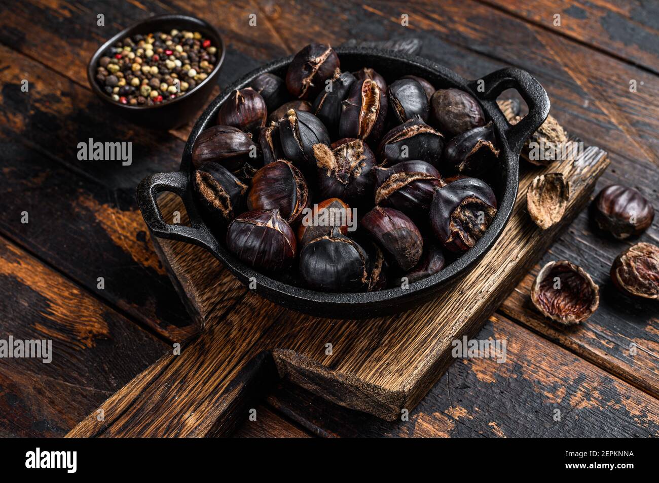 Roasted chestnuts served in a pan on a wooden cutting board. Wooden ...