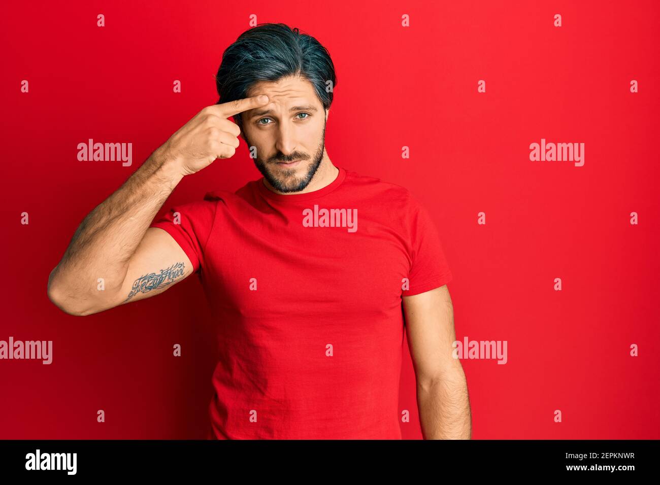Young hispanic man wearing casual red t shirt pointing unhappy to ...