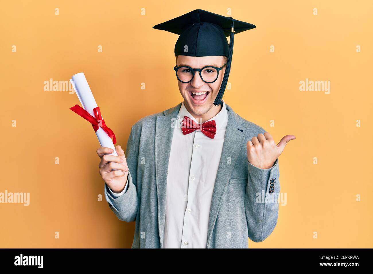 Young caucasian nerd man wearing glasses and graduation cap and holding ...