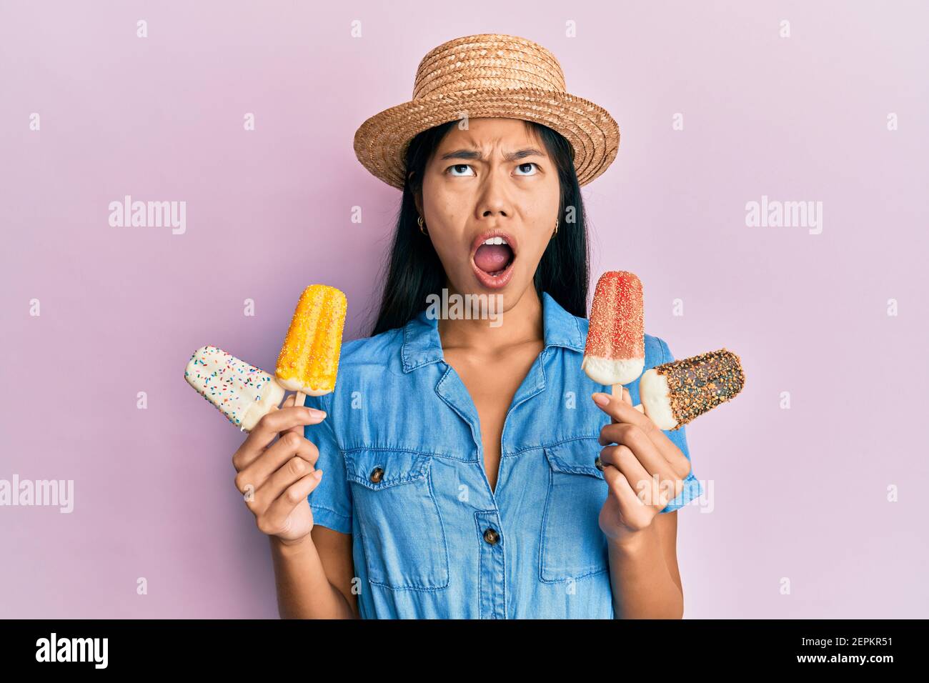 Young chinese woman wearing summer style holding ice cream angry and ...