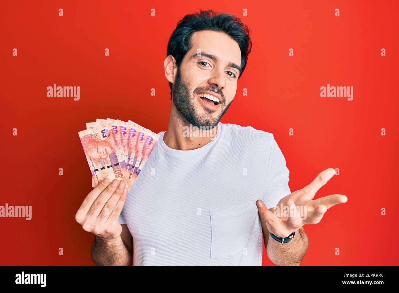 Young hispanic man holding south african rand banknotes celebrating ...