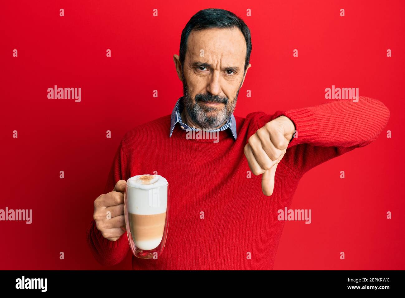 Middle age hispanic man drinking a cup of cappuccino coffee with angry ...