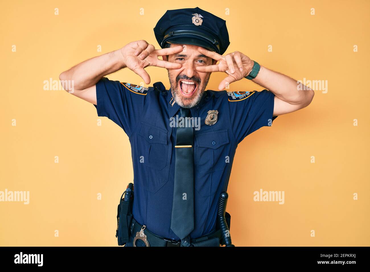 Middle age hispanic man wearing police uniform doing peace symbol with ...