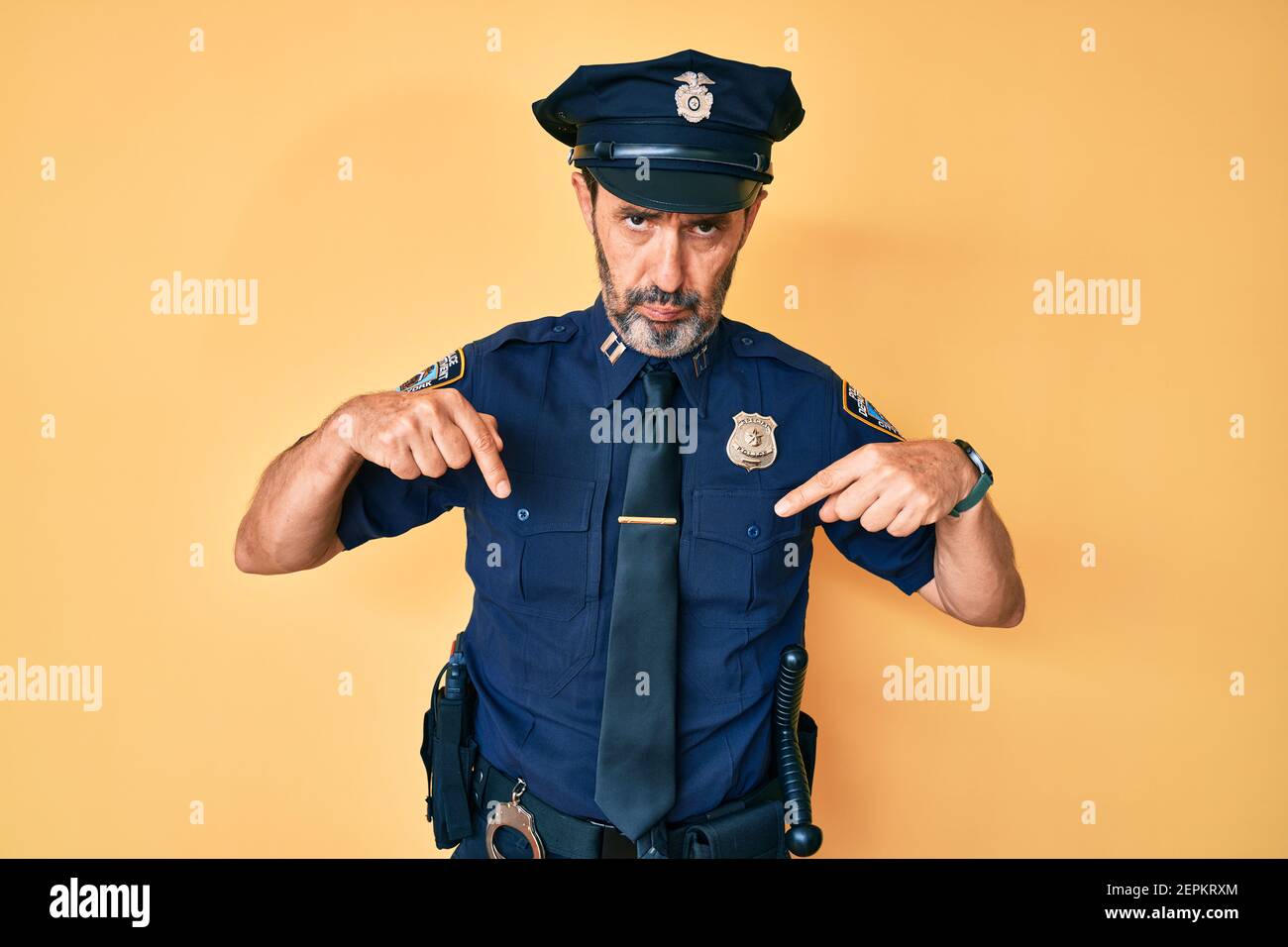 Middle age hispanic man wearing police uniform pointing down looking ...