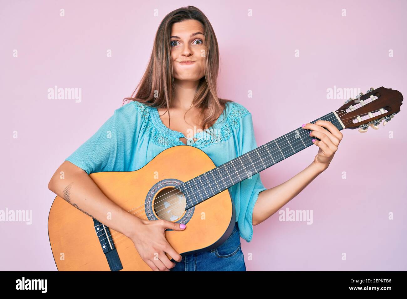 Beautiful caucasian woman playing classical guitar puffing cheeks with ...