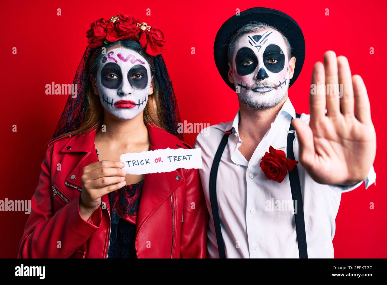 Couple wearing day of the dead costume holding trick or treat paper ...
