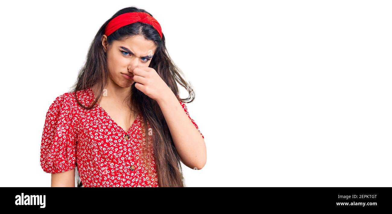 Brunette teenager girl wearing summer dress smelling something stinky ...
