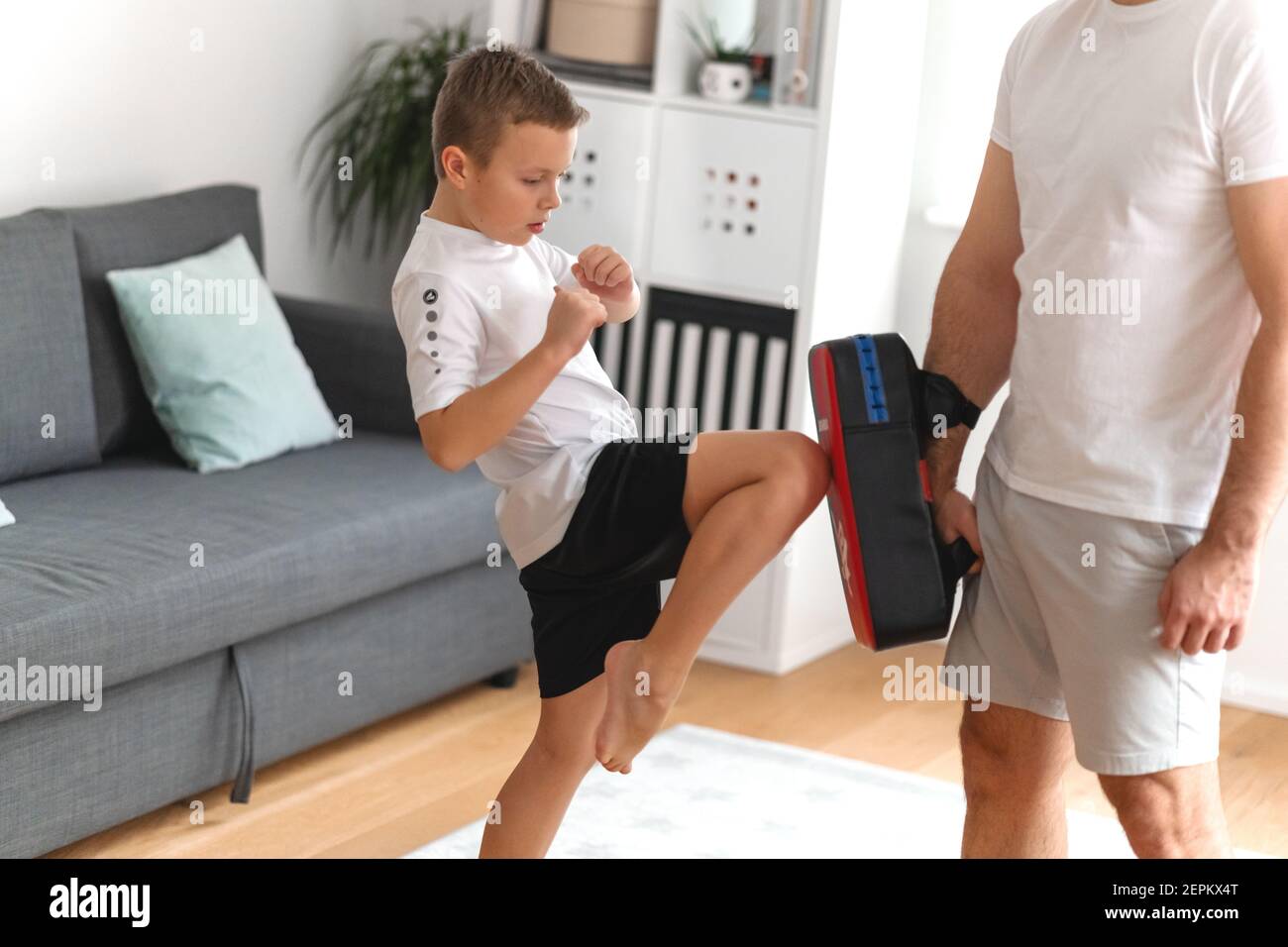 A young school boy exercising taekwondo at home with father. Training ...