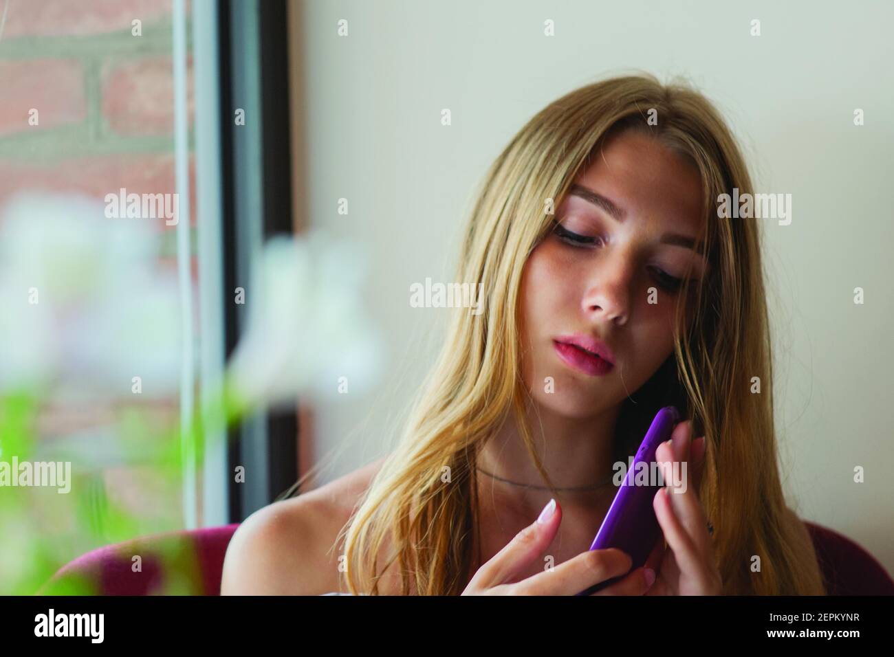 Natural blonde speaks on the phone.. Pretty girl with long hair in a cafe. The girl by the ...