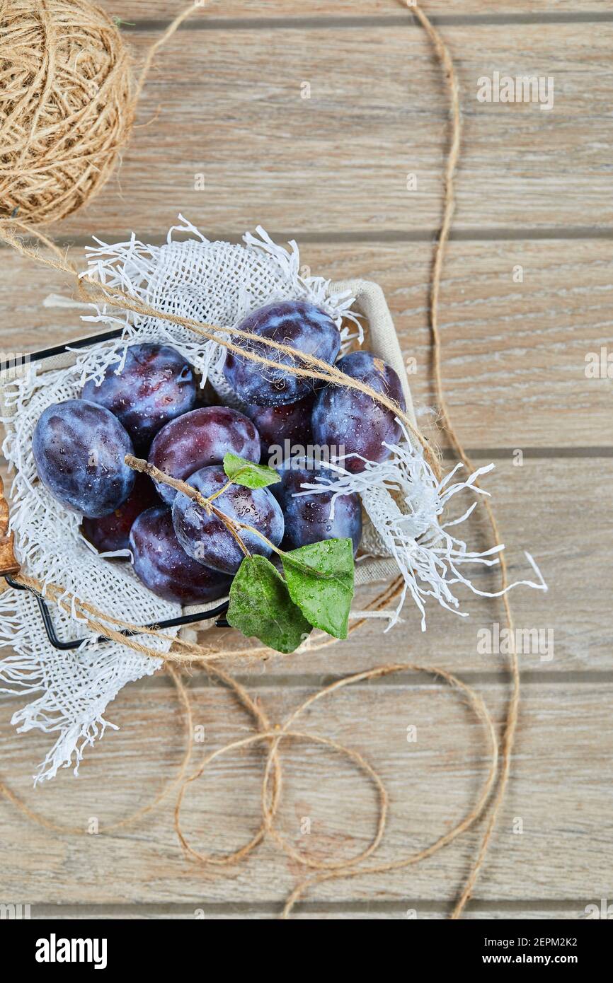 Garden plums in a basket on a wooden table Stock Photo - Alamy